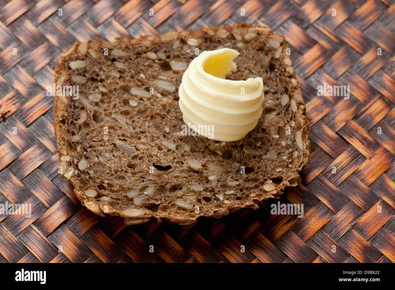 Slice of grain bread with curl of butter, close up Stock Photo - Alamy
