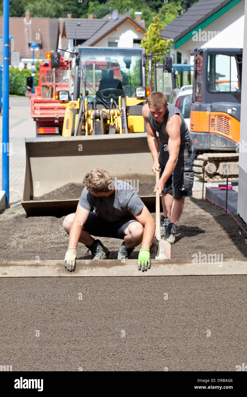 Germany, Rhineland Palatinate, Young men pulling smooth grit layer ...