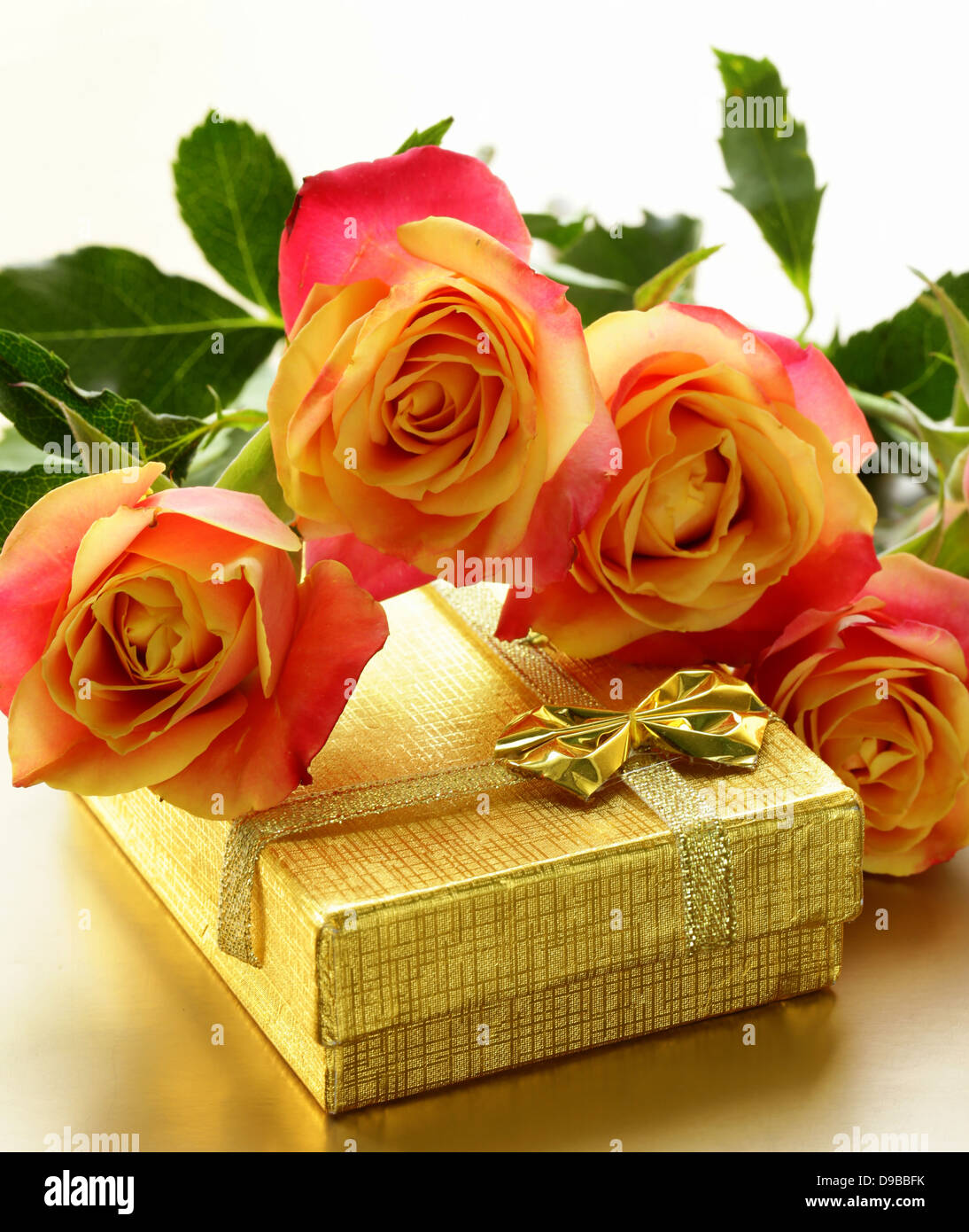 orange roses and box with gifts on gold background Stock Photo - Alamy