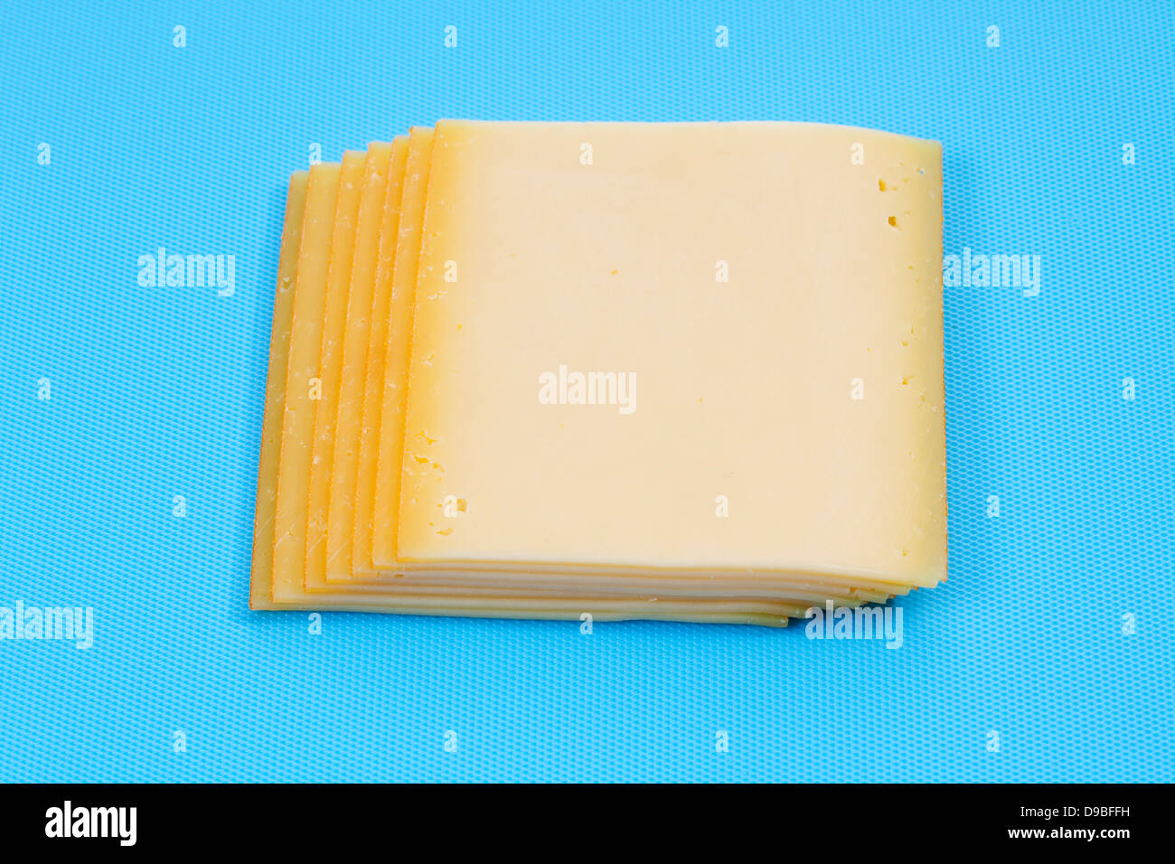 Slices of Gouda Cheese on blue background Stock Photo - Alamy