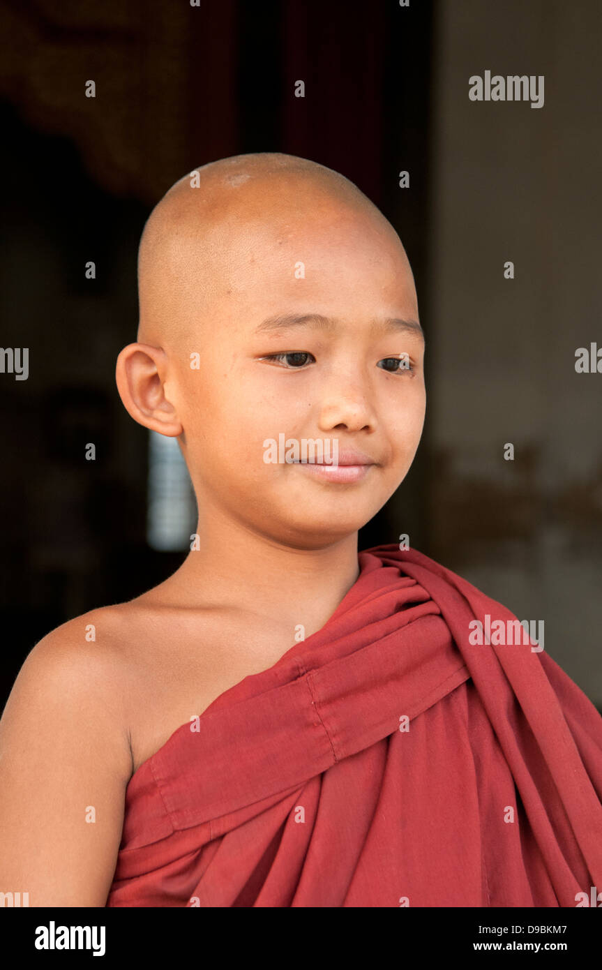 Boy monk in red robes stands in doorway of a temple Myanmar Burma Stock ...