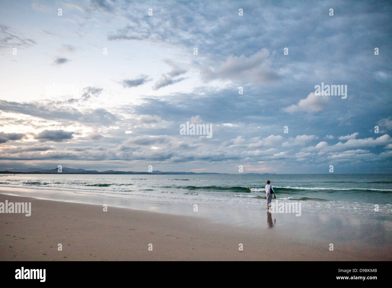 A woman stands on a deserted beach looking out to sea Stock Photo - Alamy