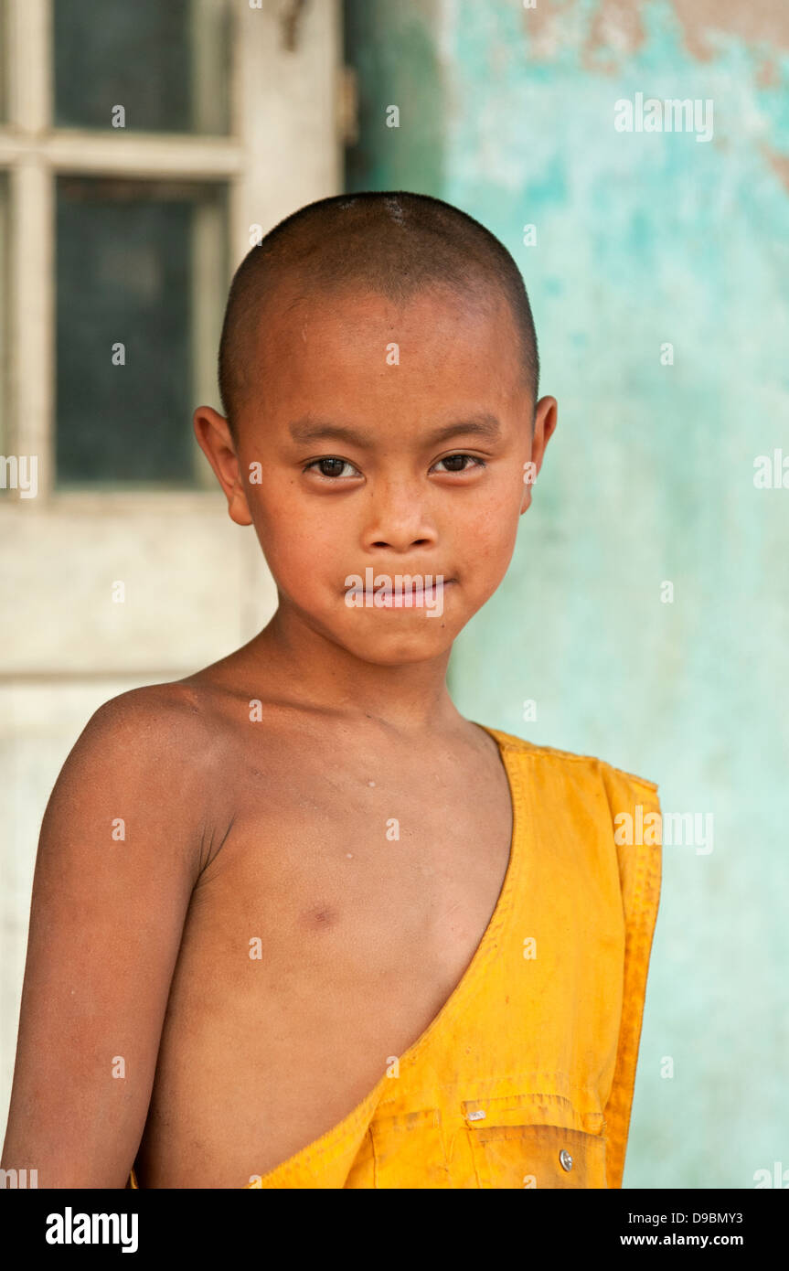 Boy monk in yellow robes stands in a temple doorway Myanmar Burma Stock ...