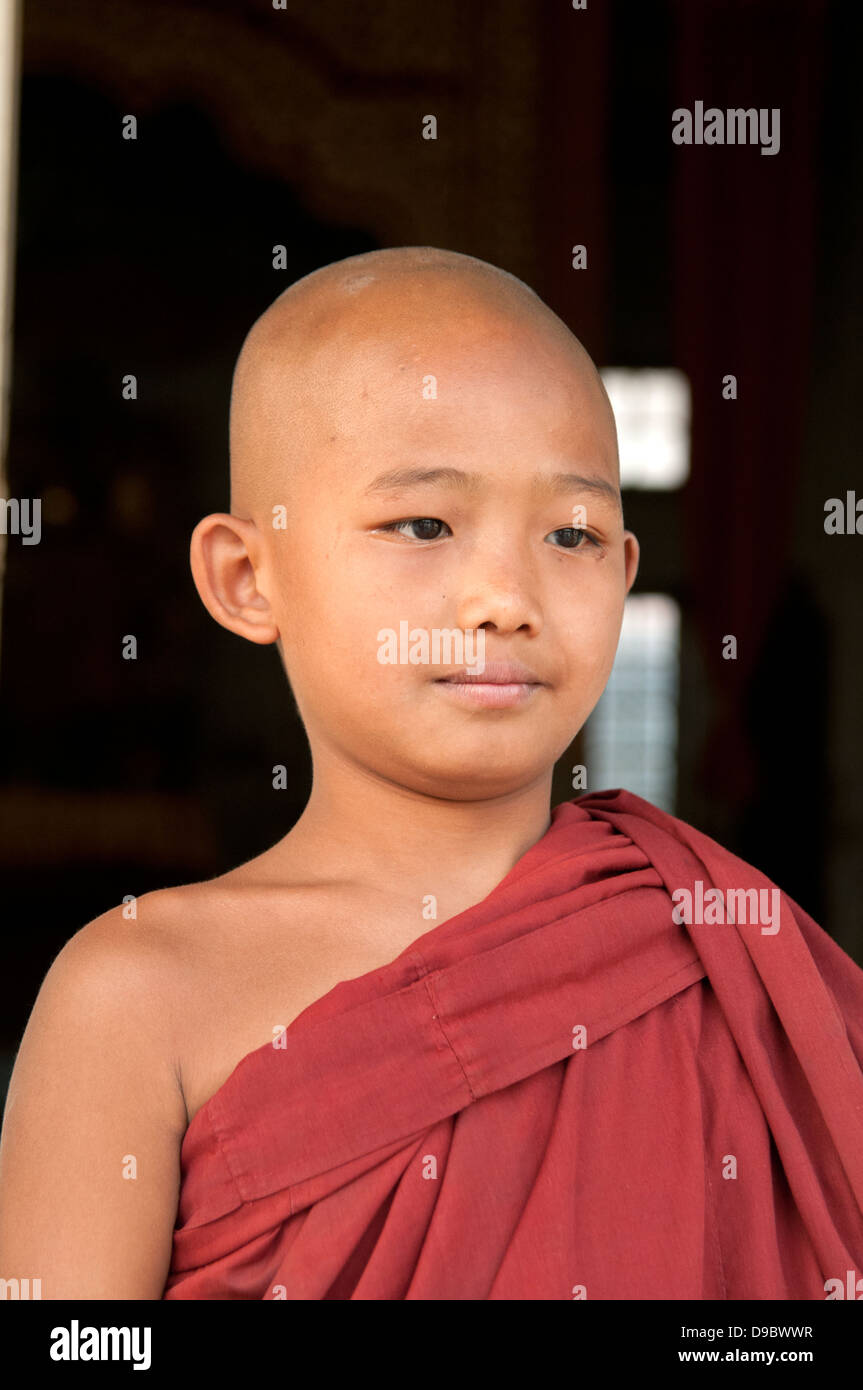 Boy monk in red robes stands in doorway of a temple Myanmar Burma Stock ...
