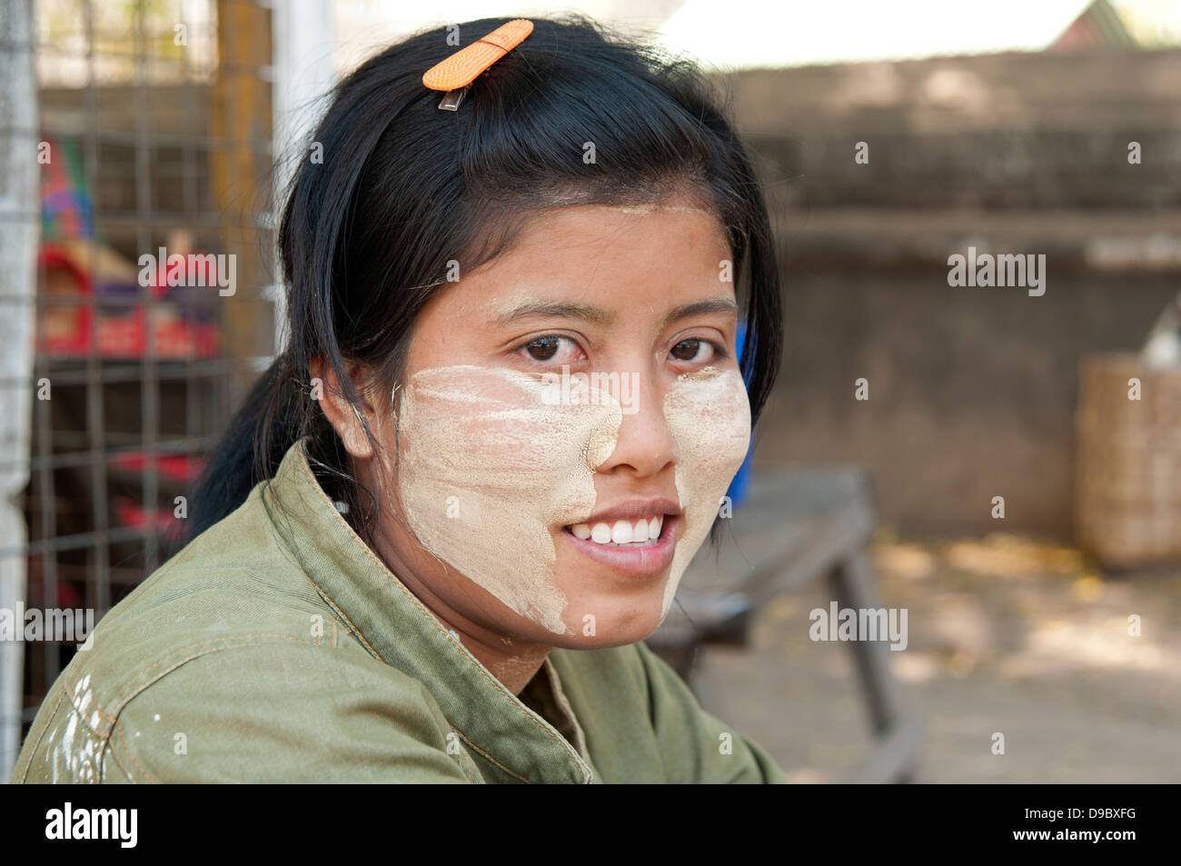 Head and shoulders portrait of a pretty Burmese woman with face covered ...