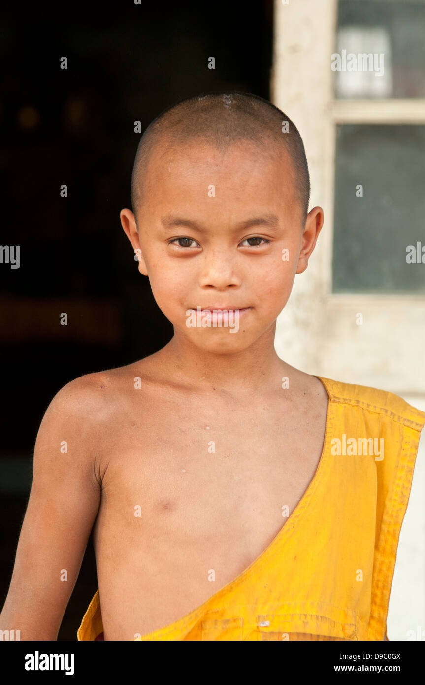 Boy monk in yellow robes stands in a temple doorway Myanmar Burma Stock ...