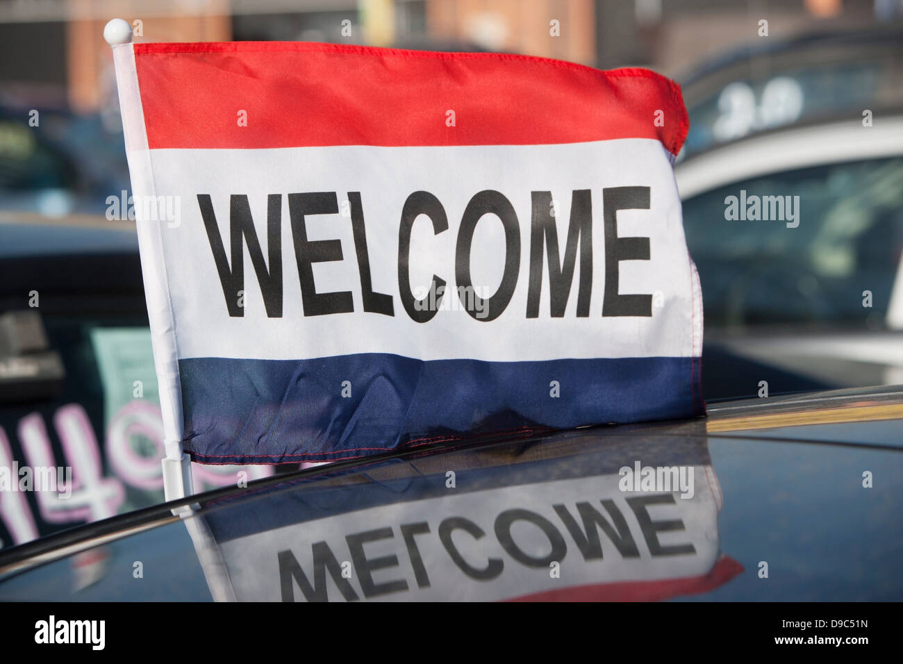 Flag saying Welcome at car dealership Stock Photo - Alamy