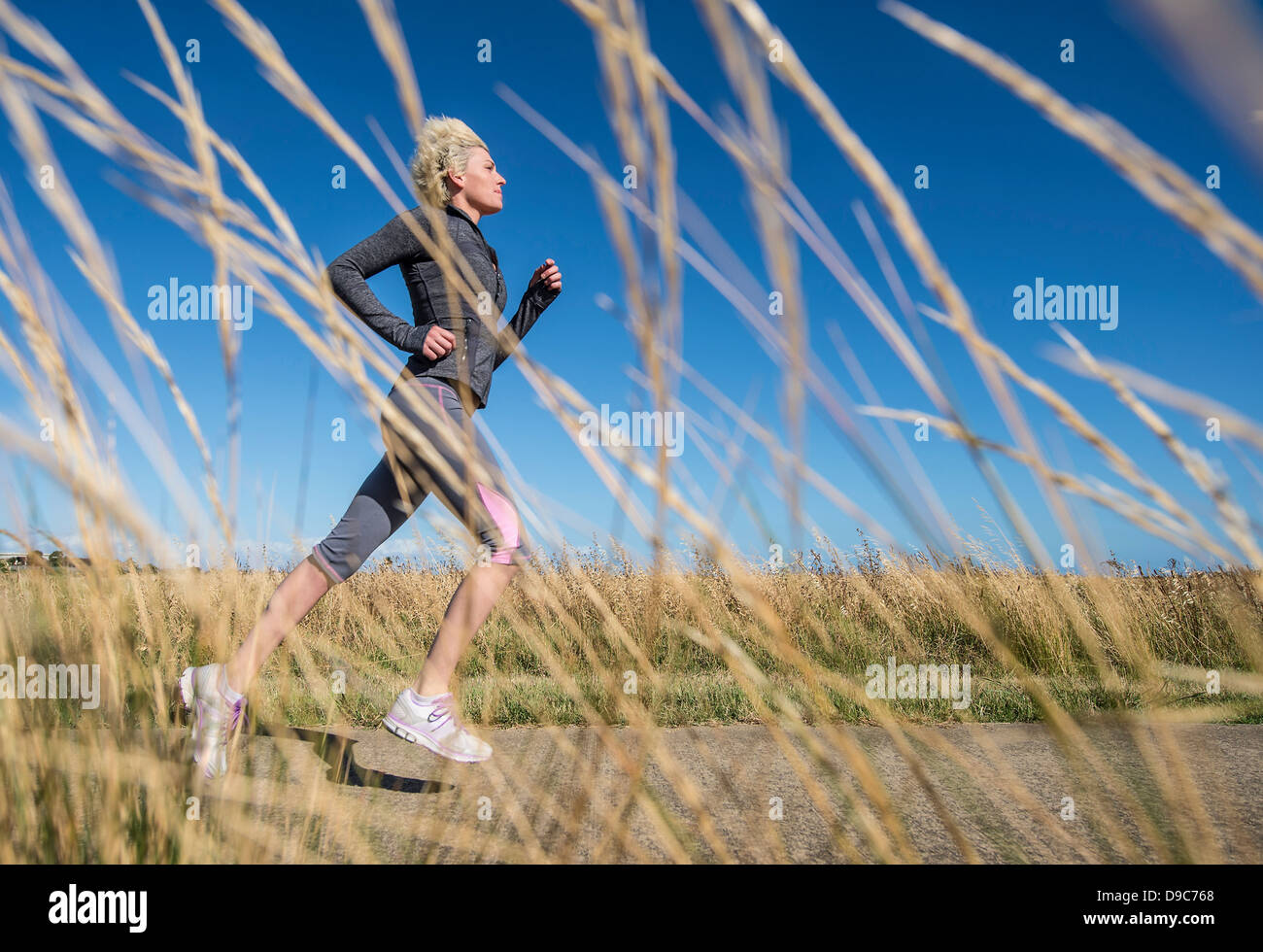 Young woman jogging, view through grass Stock Photo - Alamy