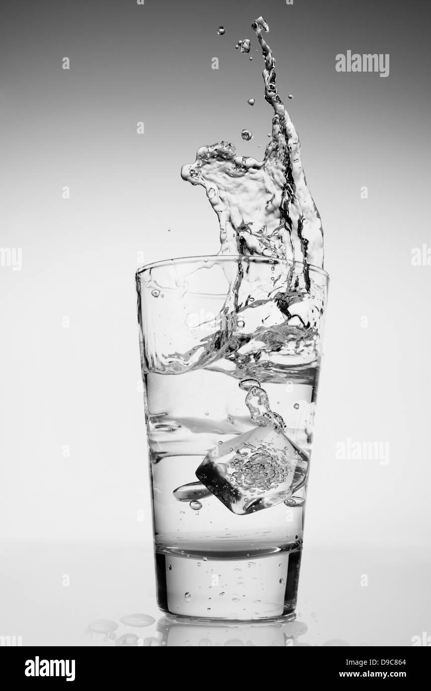 Ice cube falling into glass of water Stock Photo - Alamy