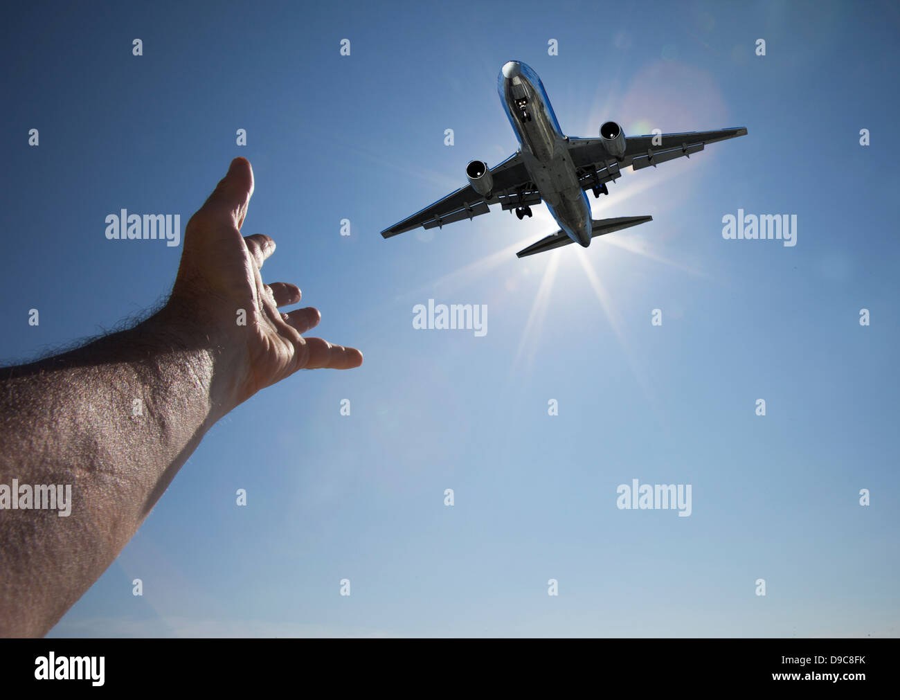 Hand reaching for aeroplane in sky Stock Photo - Alamy