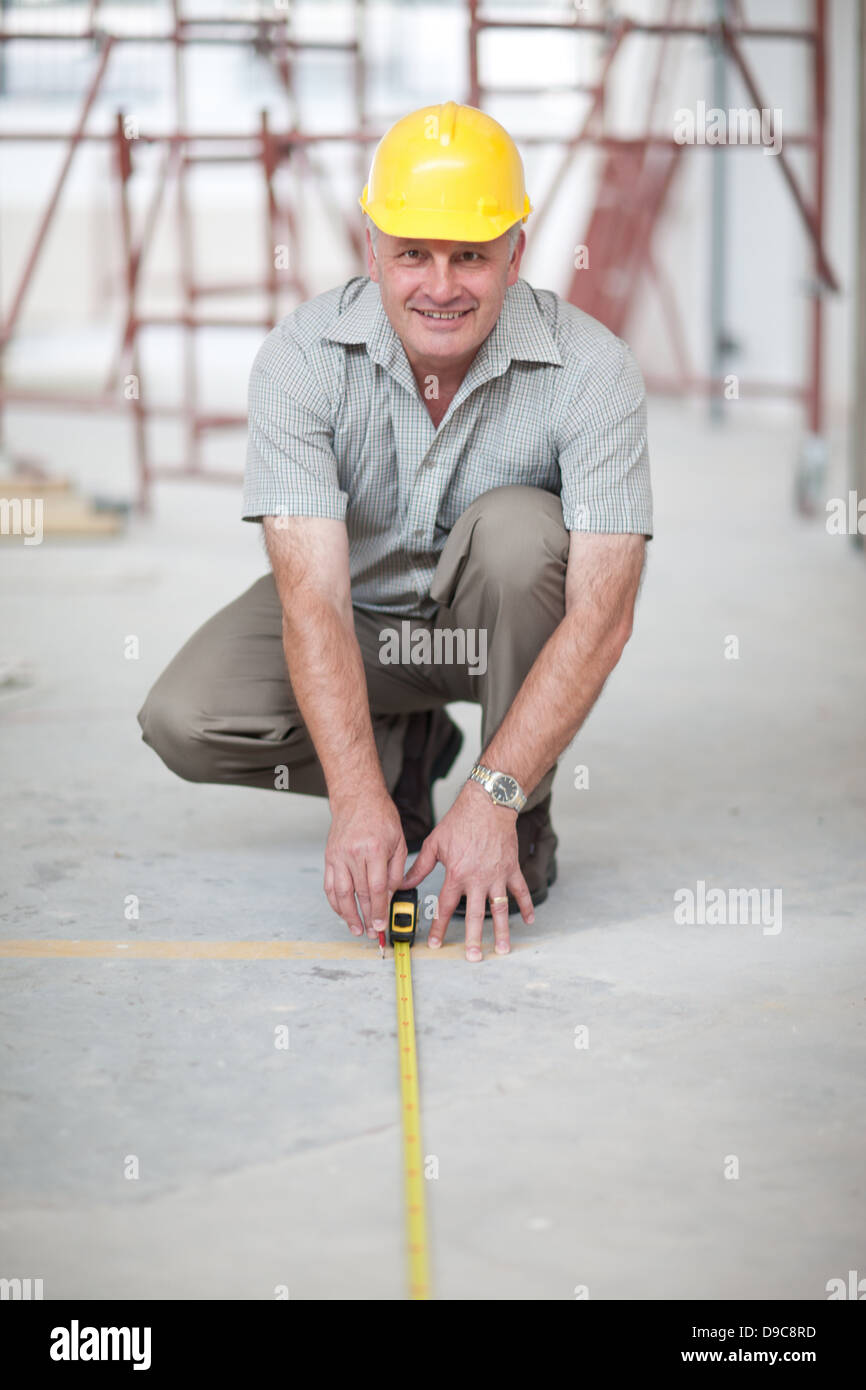 Builder measuring floor space on construction site Stock Photo - Alamy