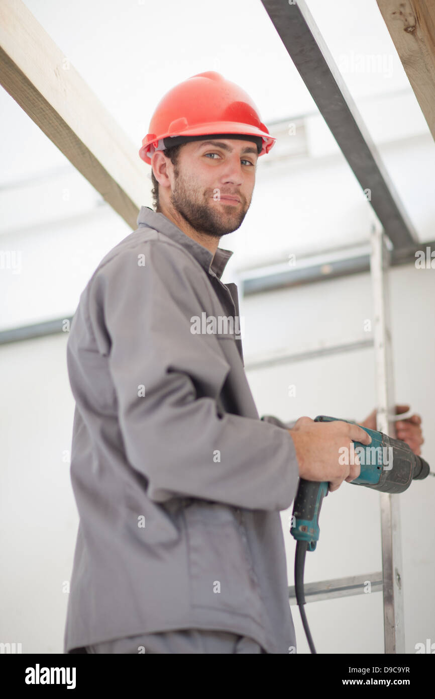 Male laborer on ladders with electric drill on construction site Stock ...