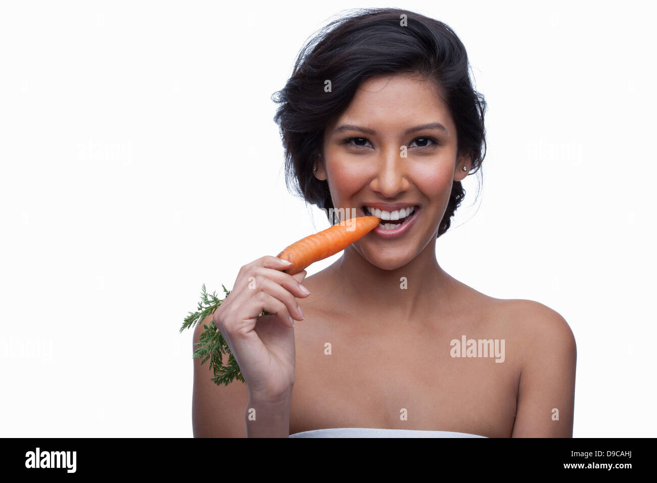 Young woman biting carrot Stock Photo - Alamy