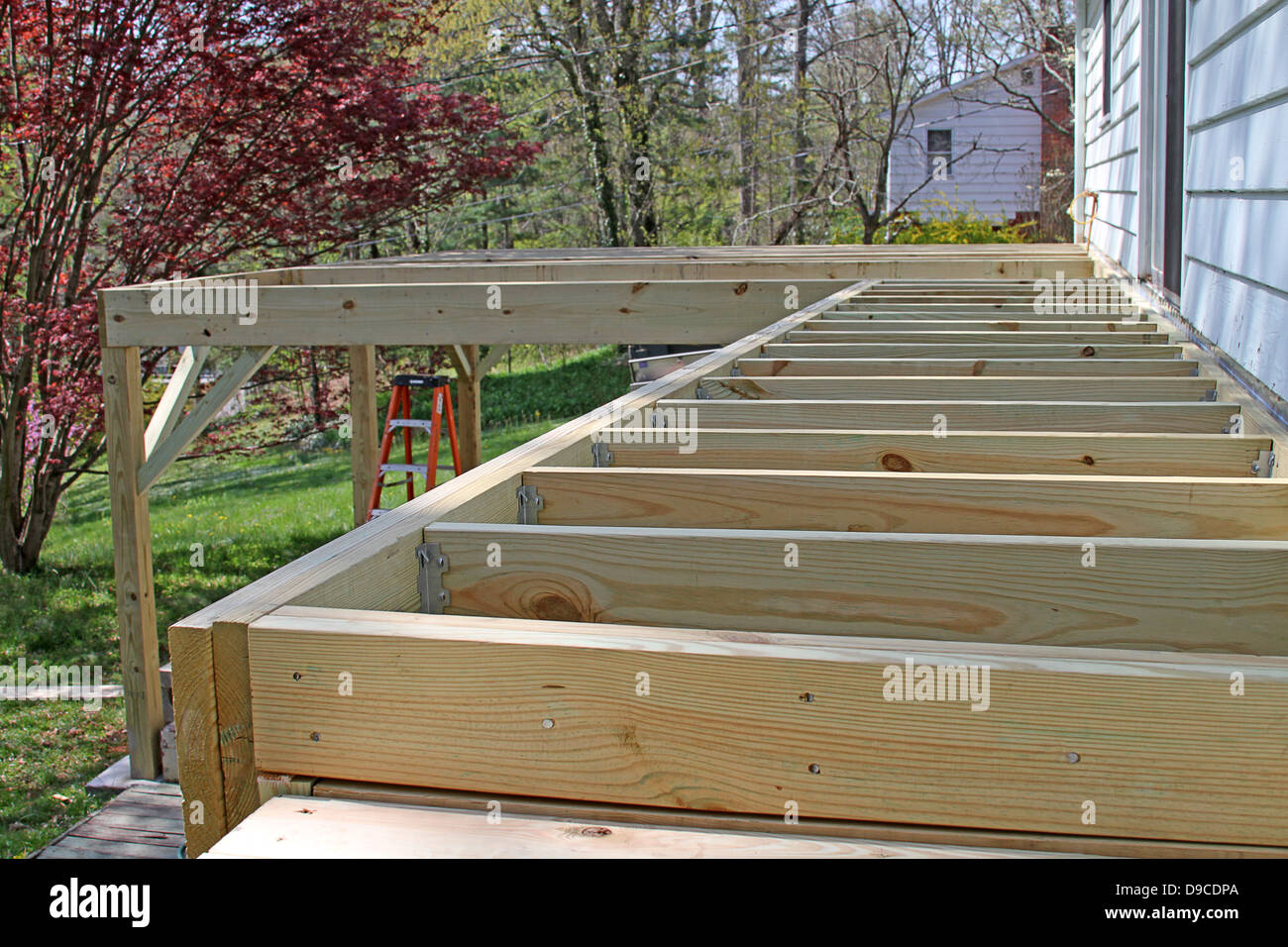 An outside wooden deck half built with slats and a ladder below Stock ...