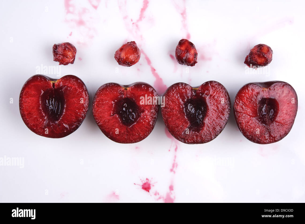 image of fresh cherries cut in halves with seeds and cherry juice on ...