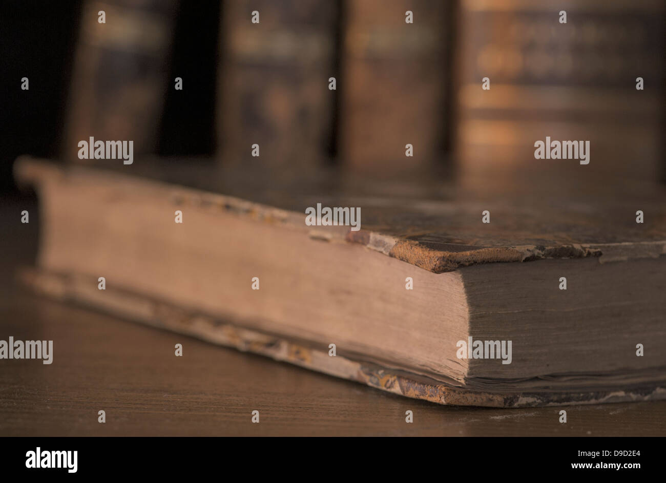 Old hardcover book with collection of books as background. Focus on ...