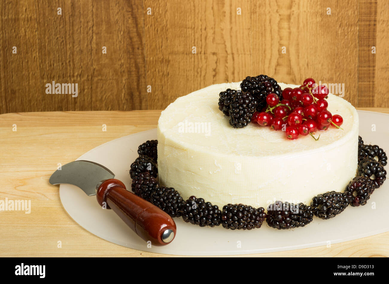 Fresh round of white cheddar cheese with knife and berries Stock Photo ...