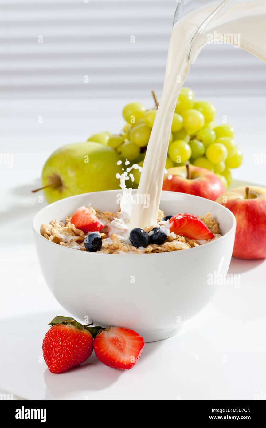 Bowl of cornflakes with various fruits and pouring milk, close up Stock ...