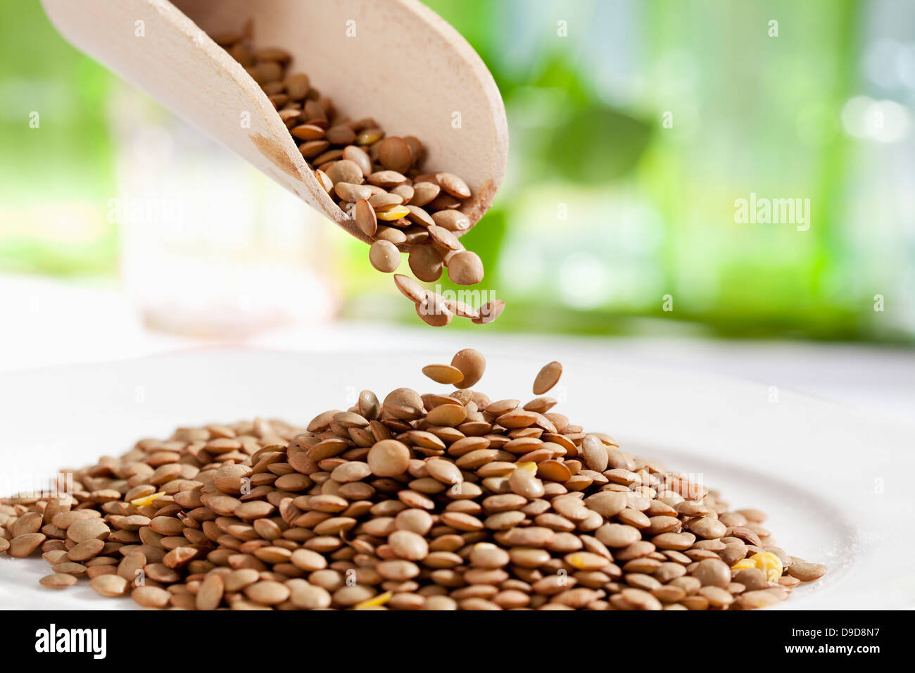 Lentils pouring from wooden scoop, close up Stock Photo - Alamy