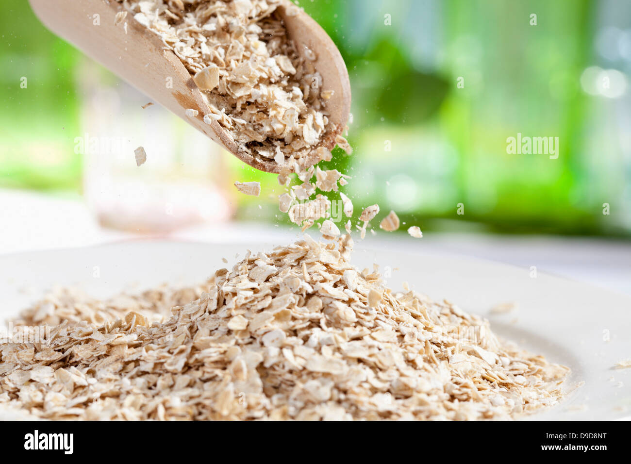 Oat flakes pouring from wooden scoop, close up Stock Photo - Alamy
