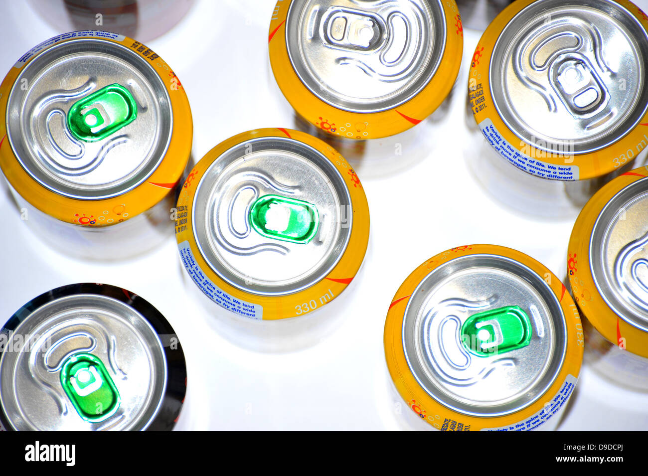 The tops of a variety of cans of fizzy pop photographed against a white ...