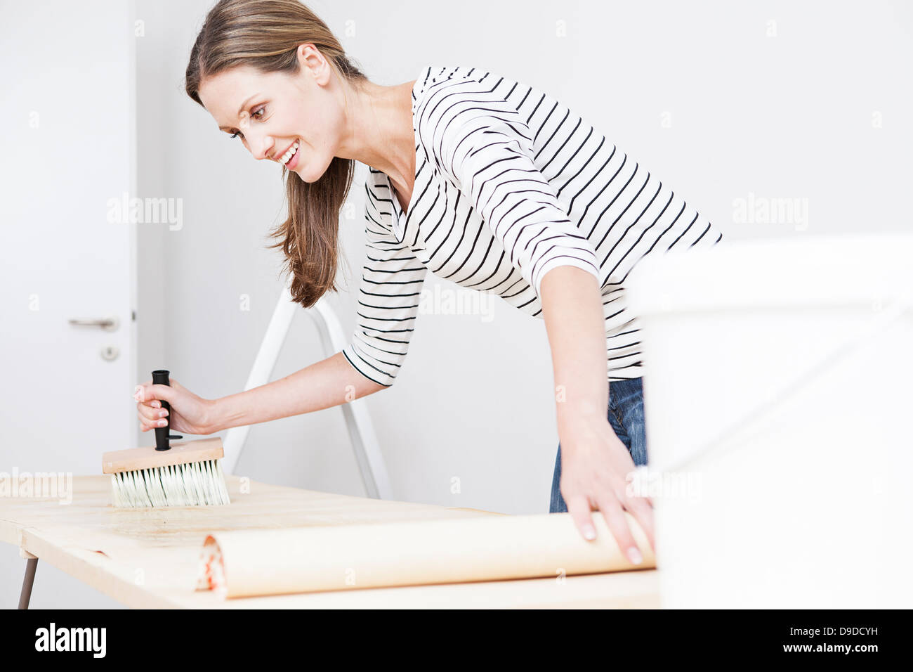 Woman applying glue on wallpaper Stock Photo - Alamy