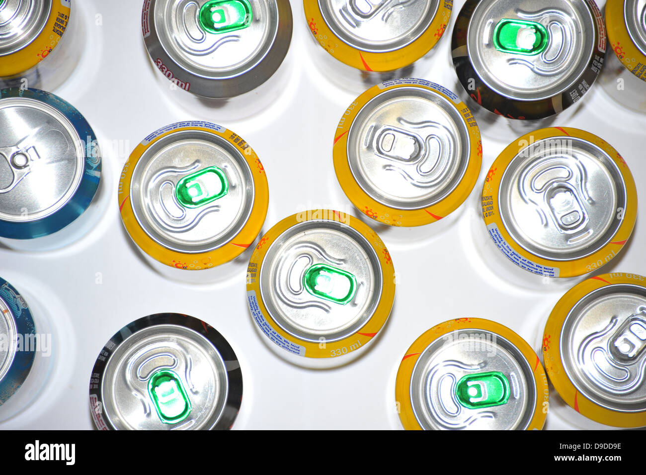 The tops of a variety of cans of fizzy pop photographed against a white ...