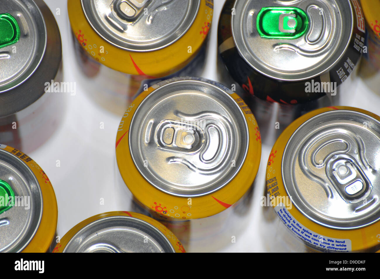 The tops of a variety of cans of fizzy pop photographed against a white ...