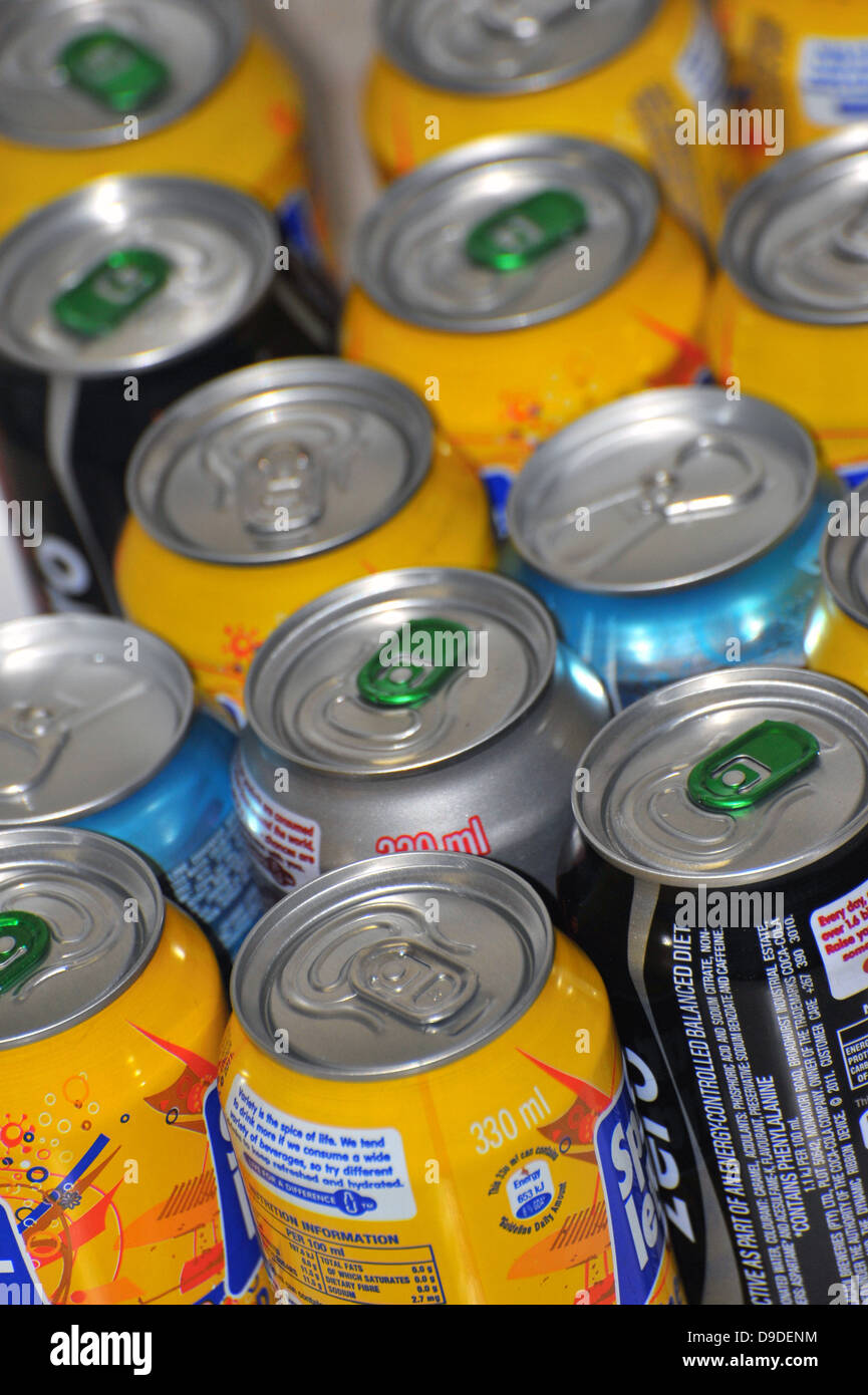 The tops of a variety of cans of fizzy pop photographed against a white ...