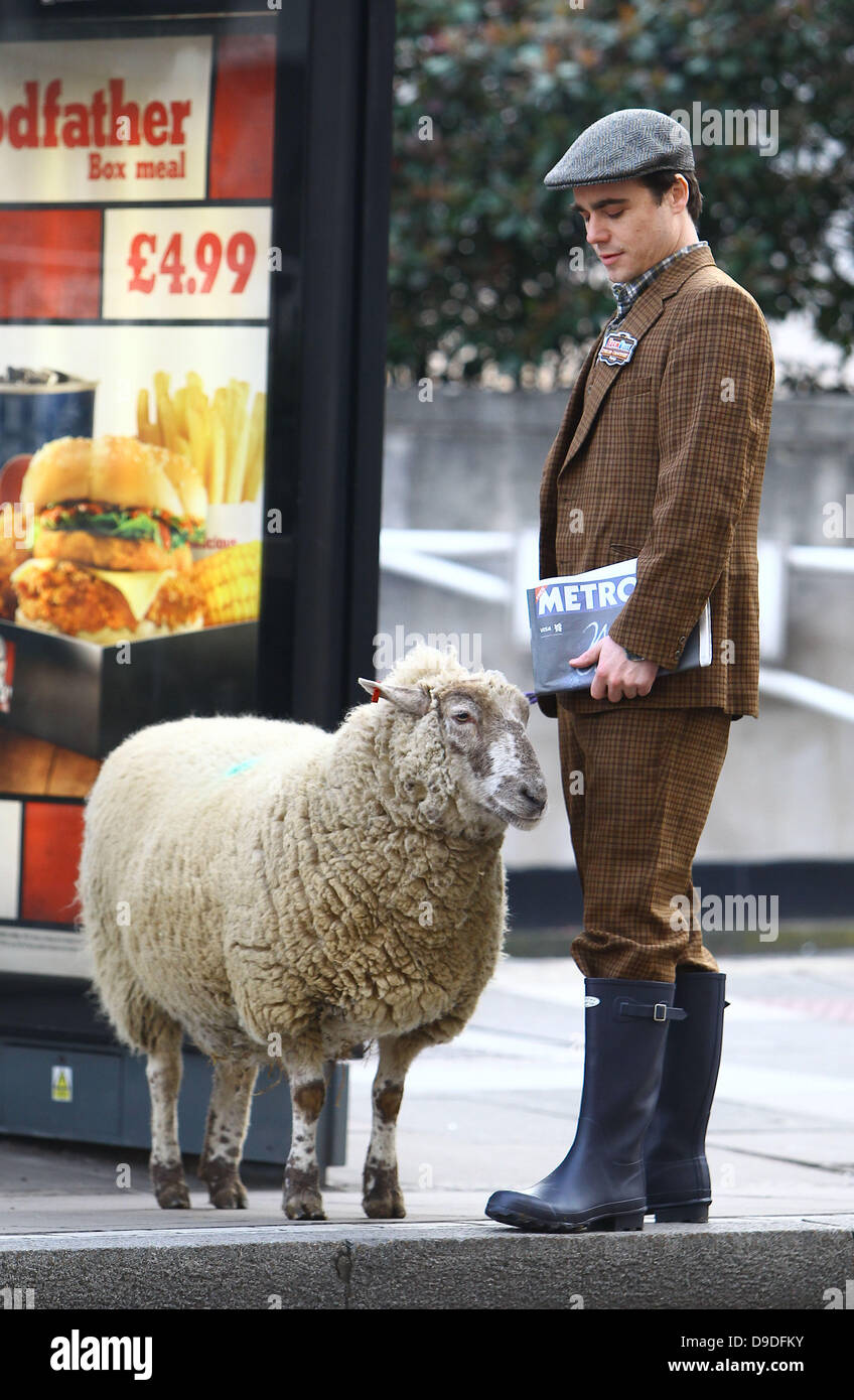 An actor dressed as an English country gentleman waits at a bus stop ...