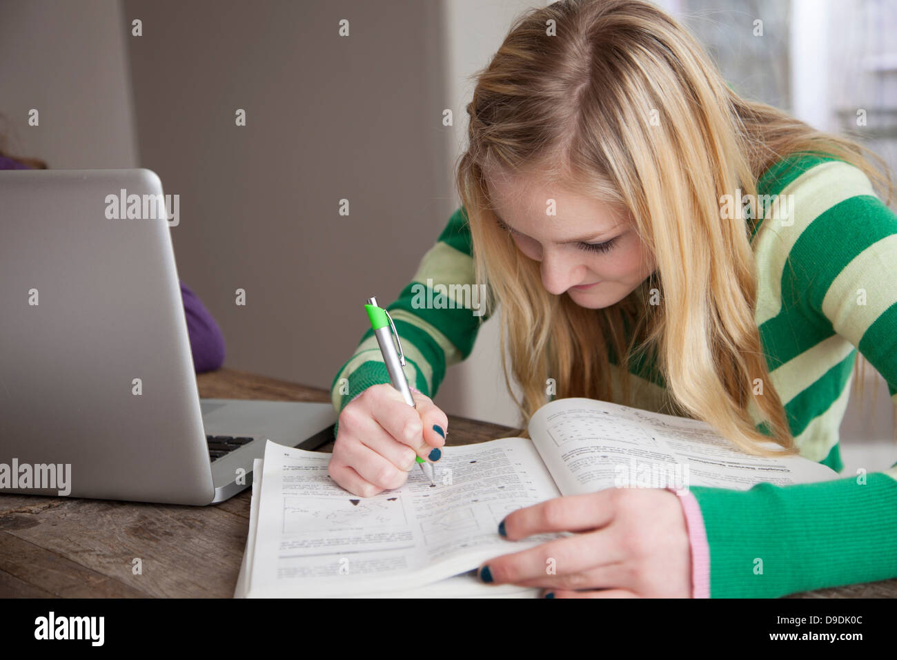 Girl sitting at table studying Stock Photo - Alamy