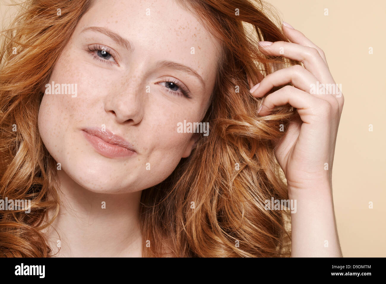 Studio shot of young woman with curly red hair, hand in hair Stock ...