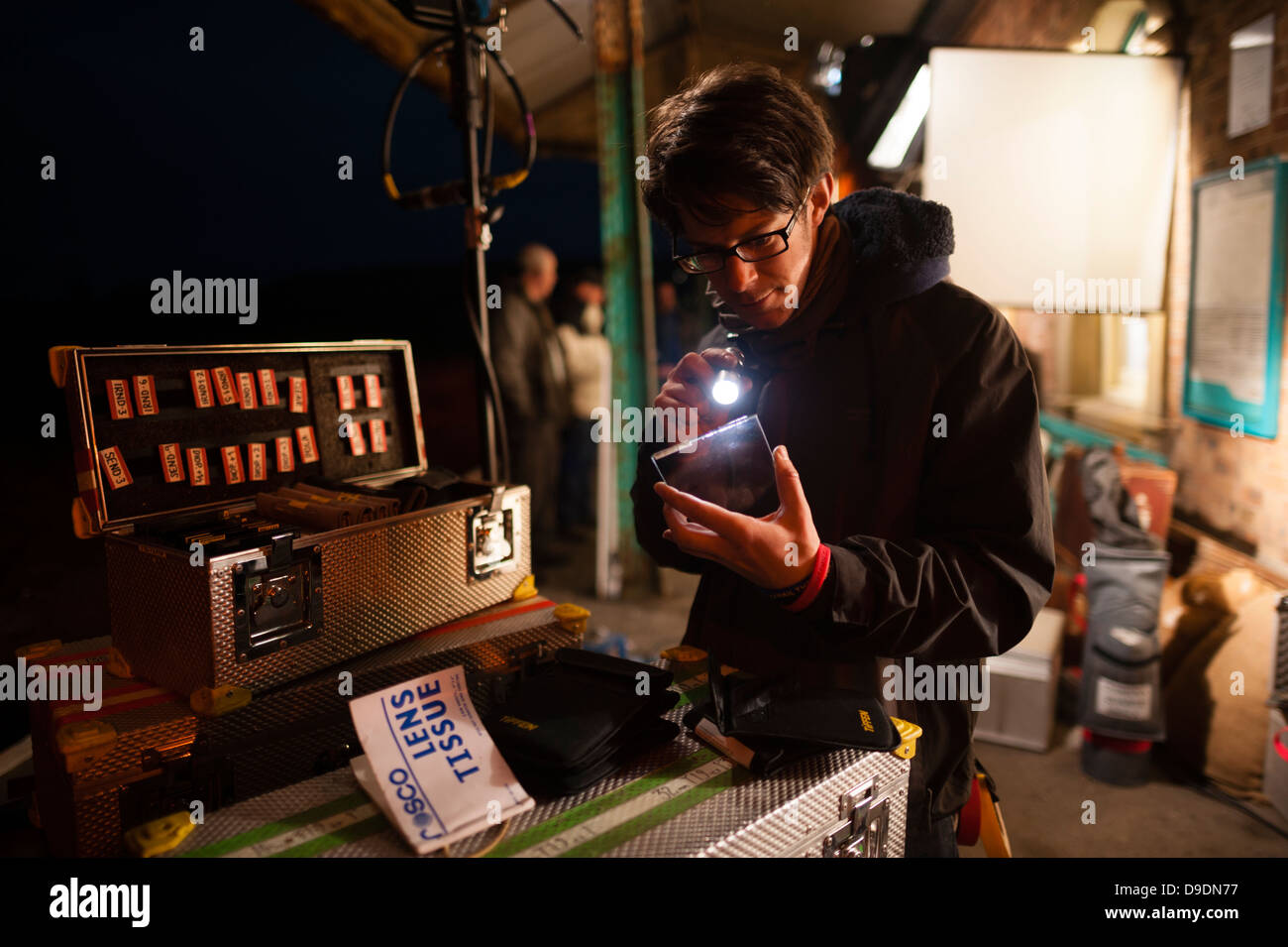 A young male assistant on a film location set shoot checking a camera ...