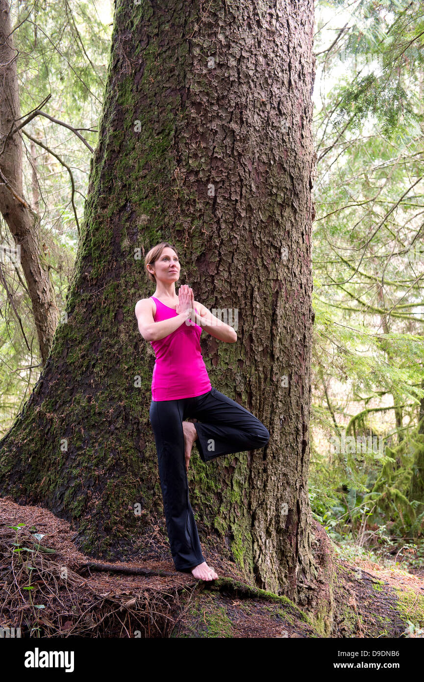 Mature woman performing tree pose in forest Stock Photo - Alamy