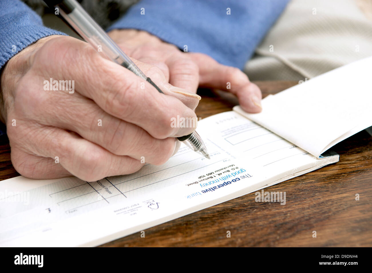 Elderly woman writing a cheque which is getting rarer these days (Co ...