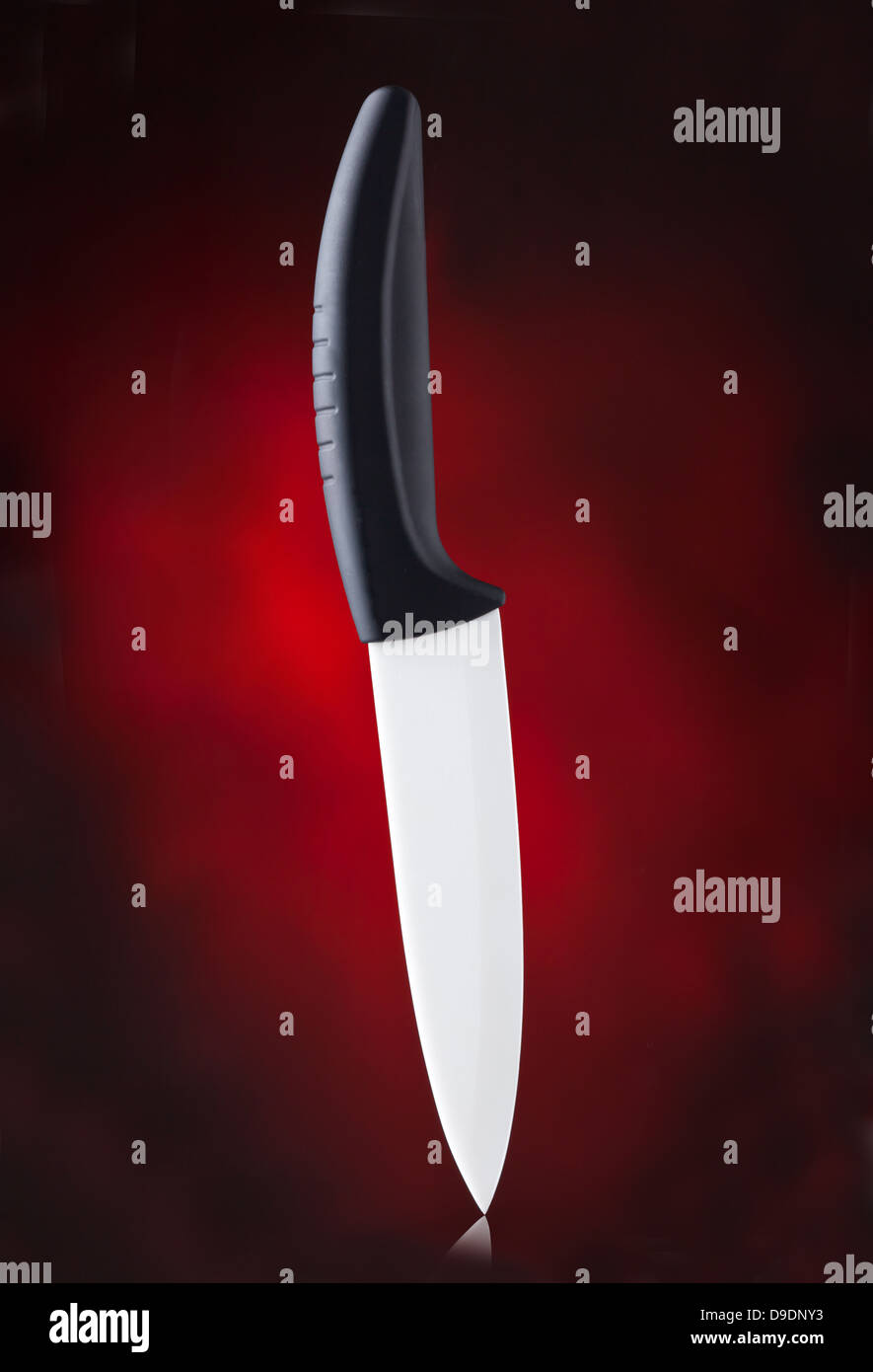 Ceramic knife on red background Stock Photo - Alamy