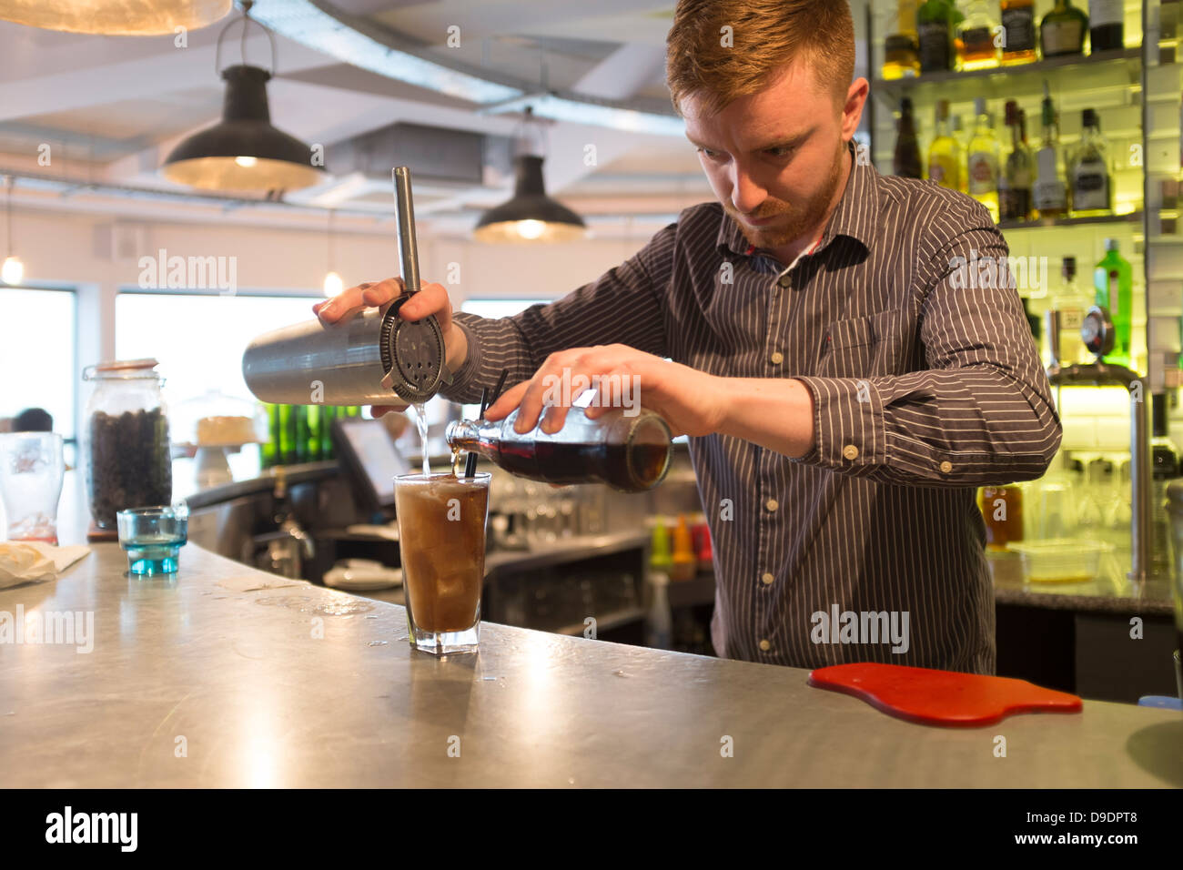 A barman mixing and pouring cocktails at Baravin cafe bar, Aberystwyth ...