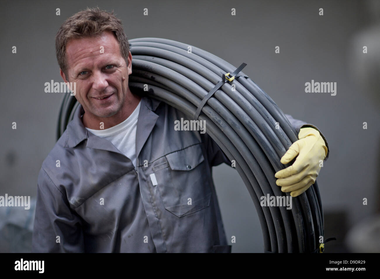 Man carrying reel of cable Stock Photo - Alamy