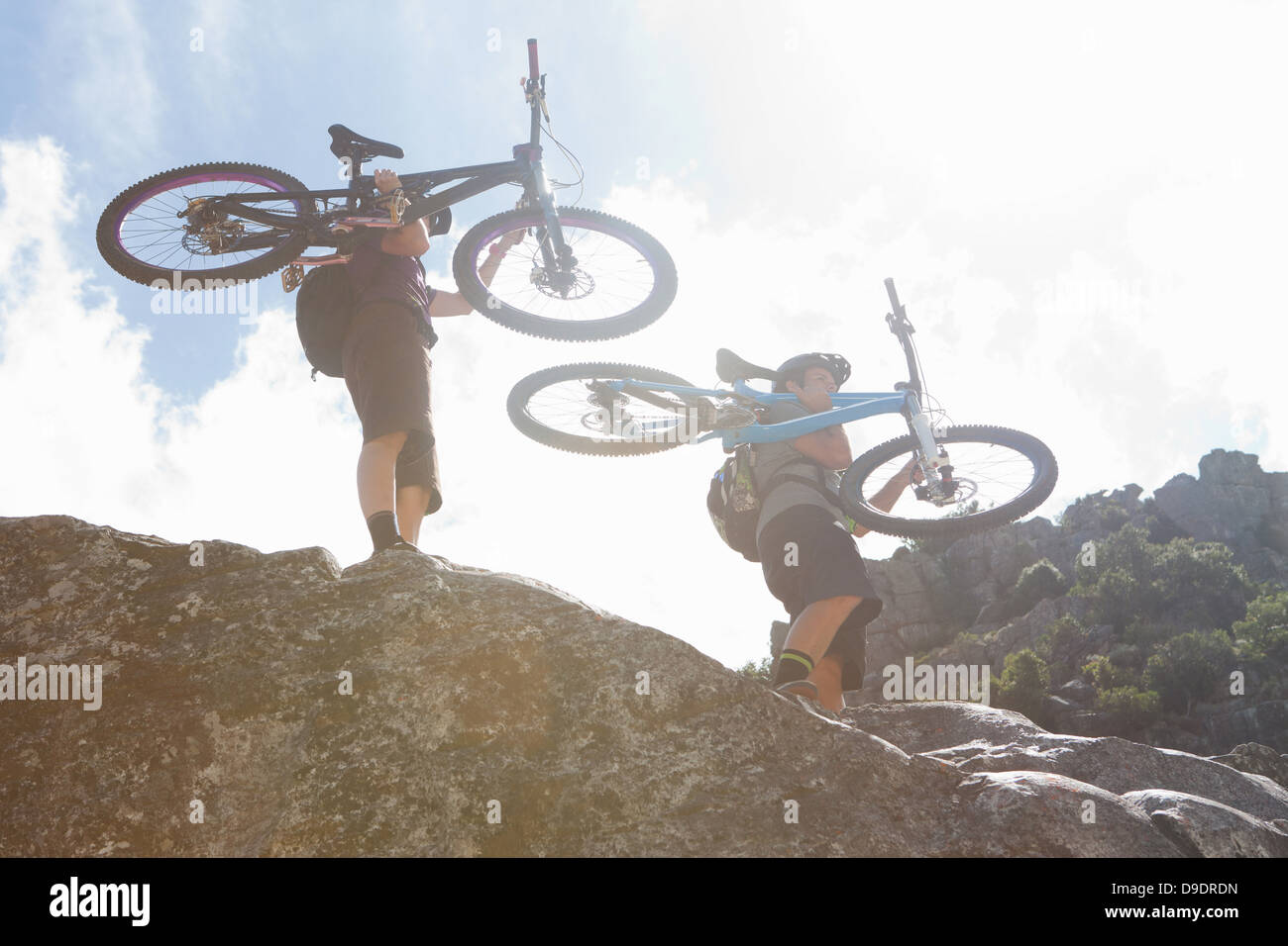 Young couple carrying mountain bikes down rocks Stock Photo - Alamy