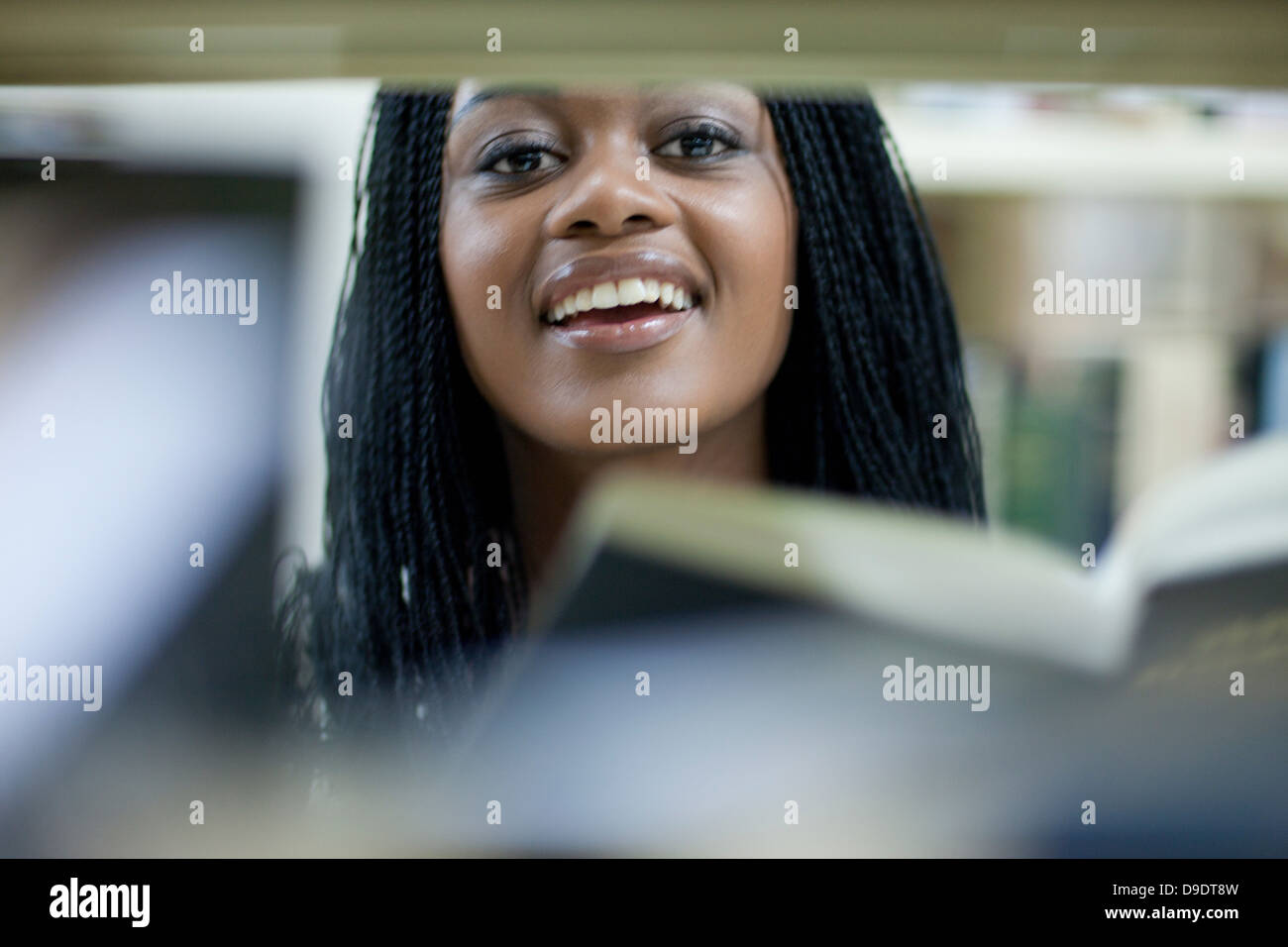 Female student peering between books Stock Photo - Alamy
