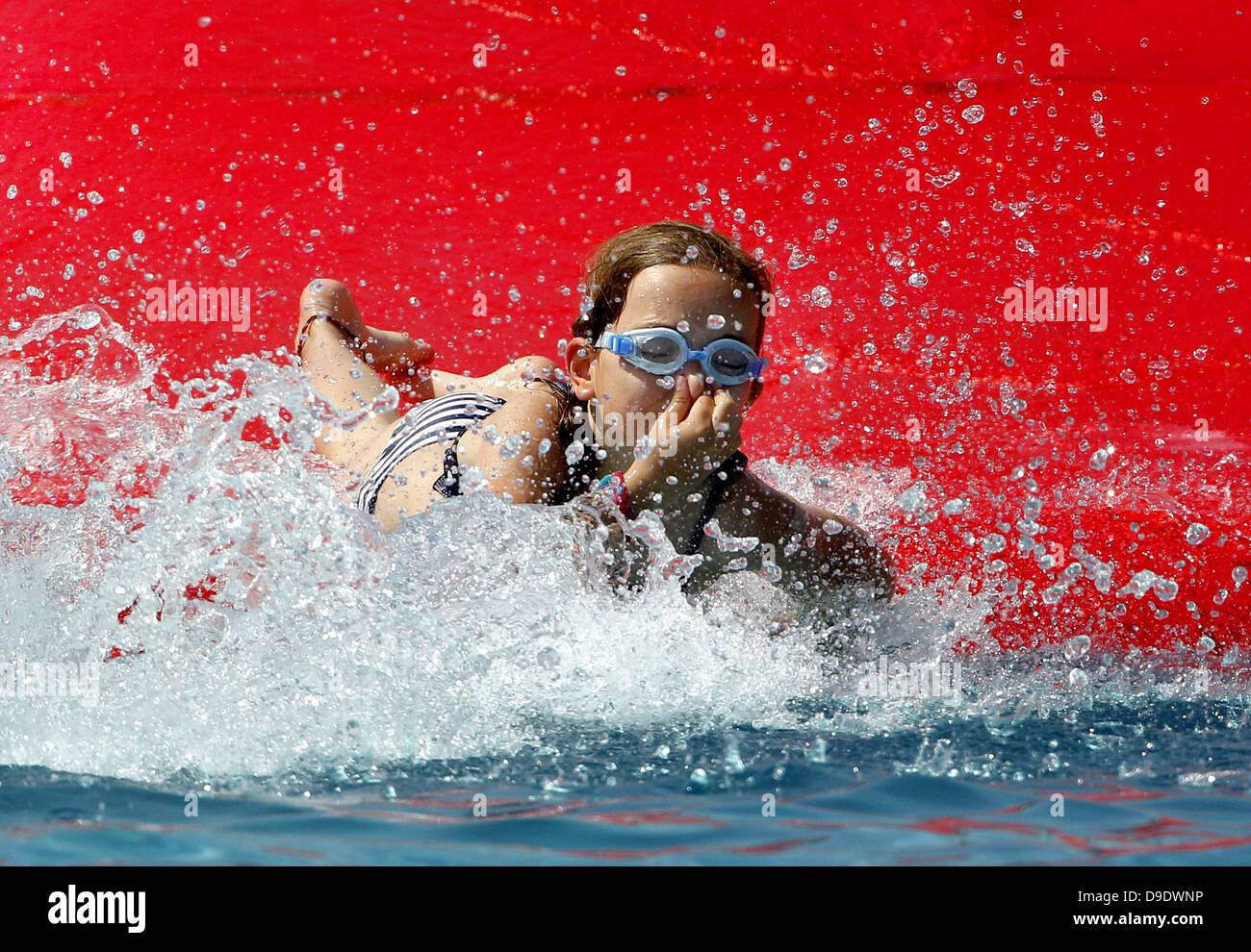 A young bather refreshes herself in the water at open-air swimming pool ...