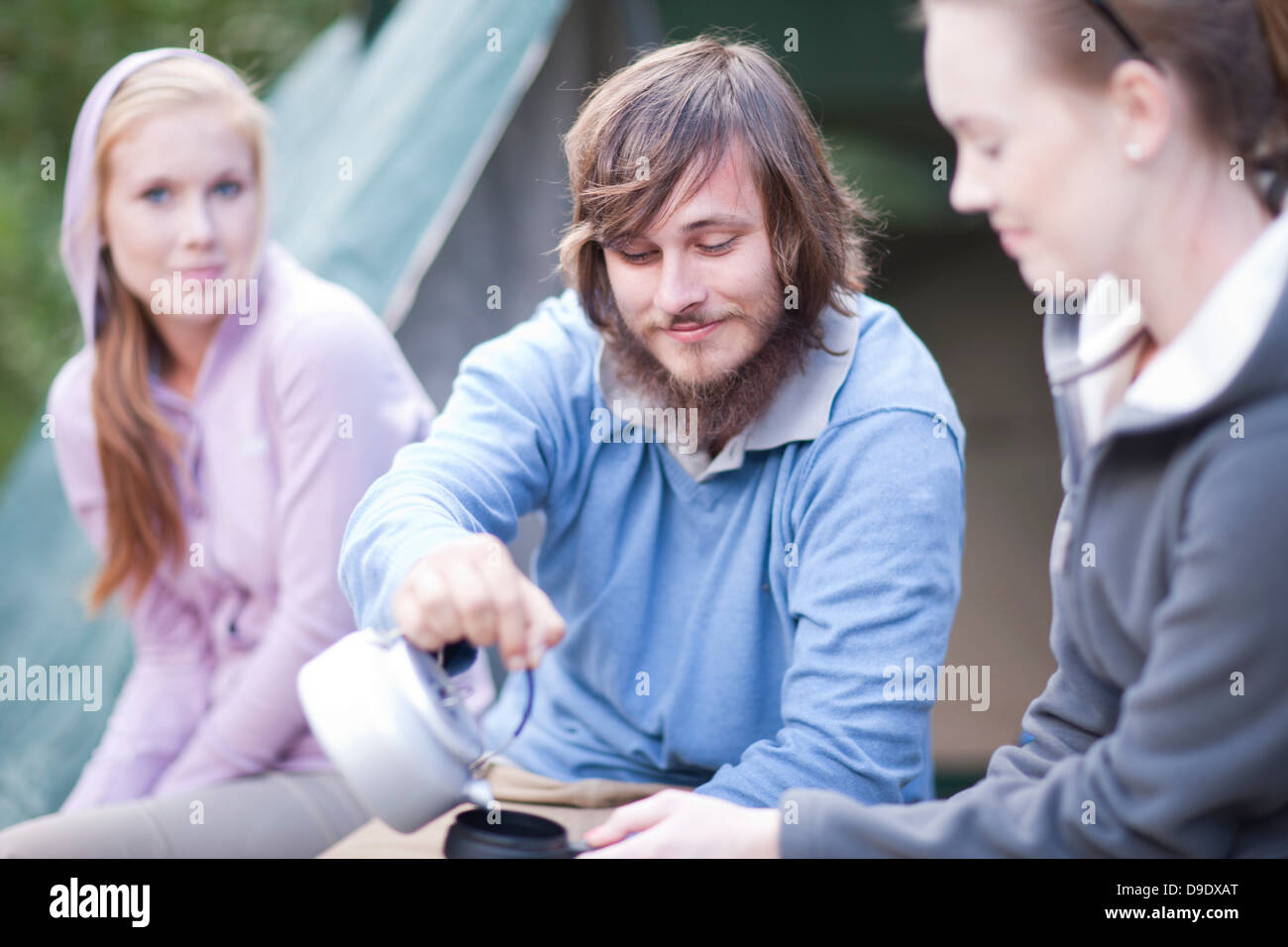 Group of young people sitting outside tent Stock Photo - Alamy