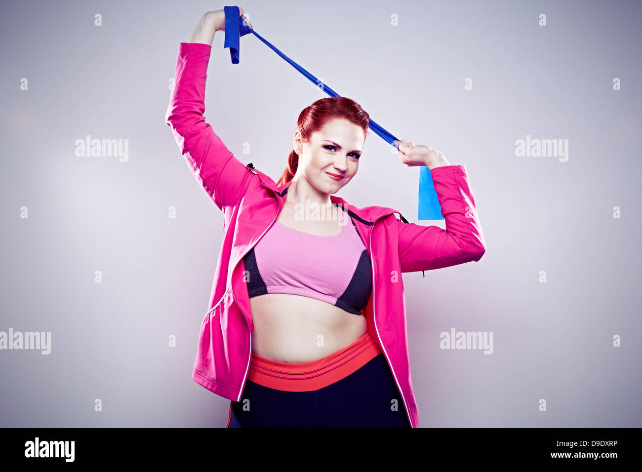 Young woman wearing pink top, stretching elastic Stock Photo - Alamy