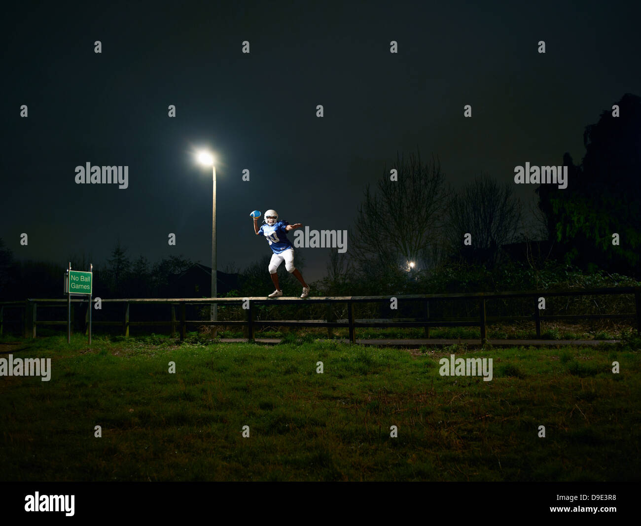 American football player taking throw from fence Stock Photo - Alamy