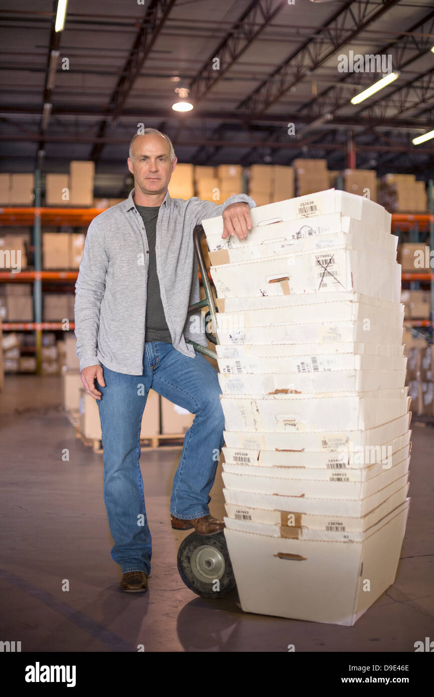 Portrait of warehouse worker standing with stack of containers Stock ...