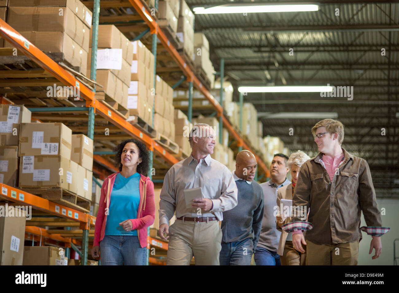 Warehouse workers walking past shelves with boxes Stock Photo - Alamy