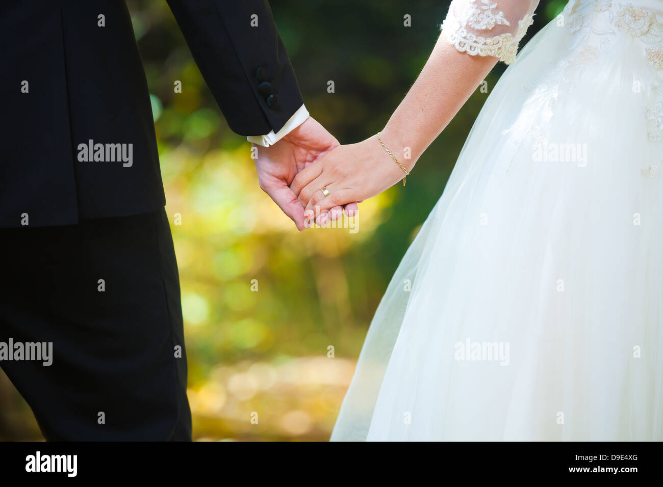 Young married couple holding hands on wedding day Stock Photo - Alamy