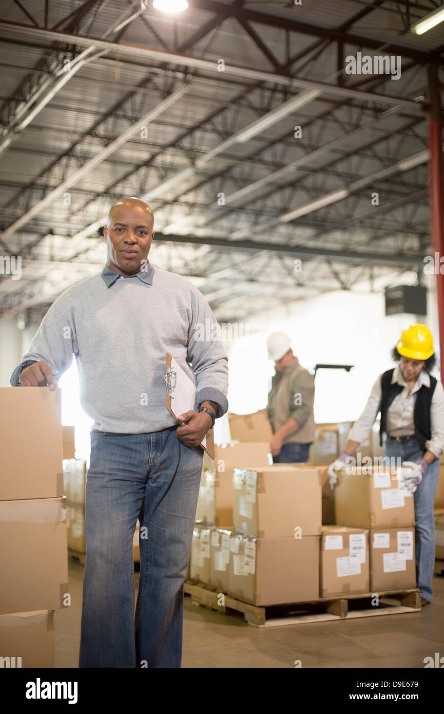 Portrait of male warehouse worker leaning on boxes Stock Photo - Alamy