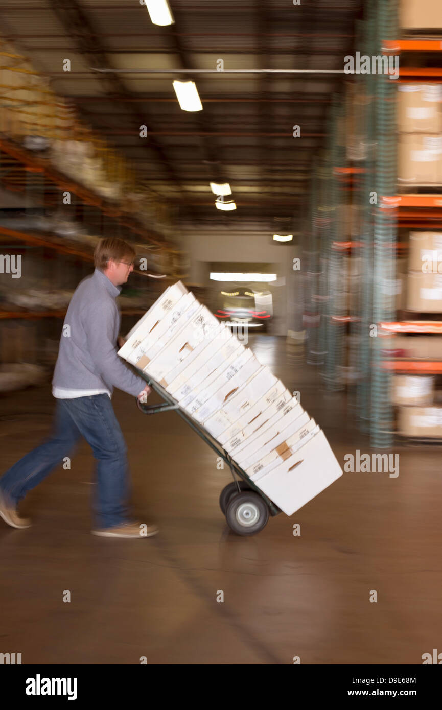 Man pushing stack of containers on trolley in warehouse Stock Photo - Alamy