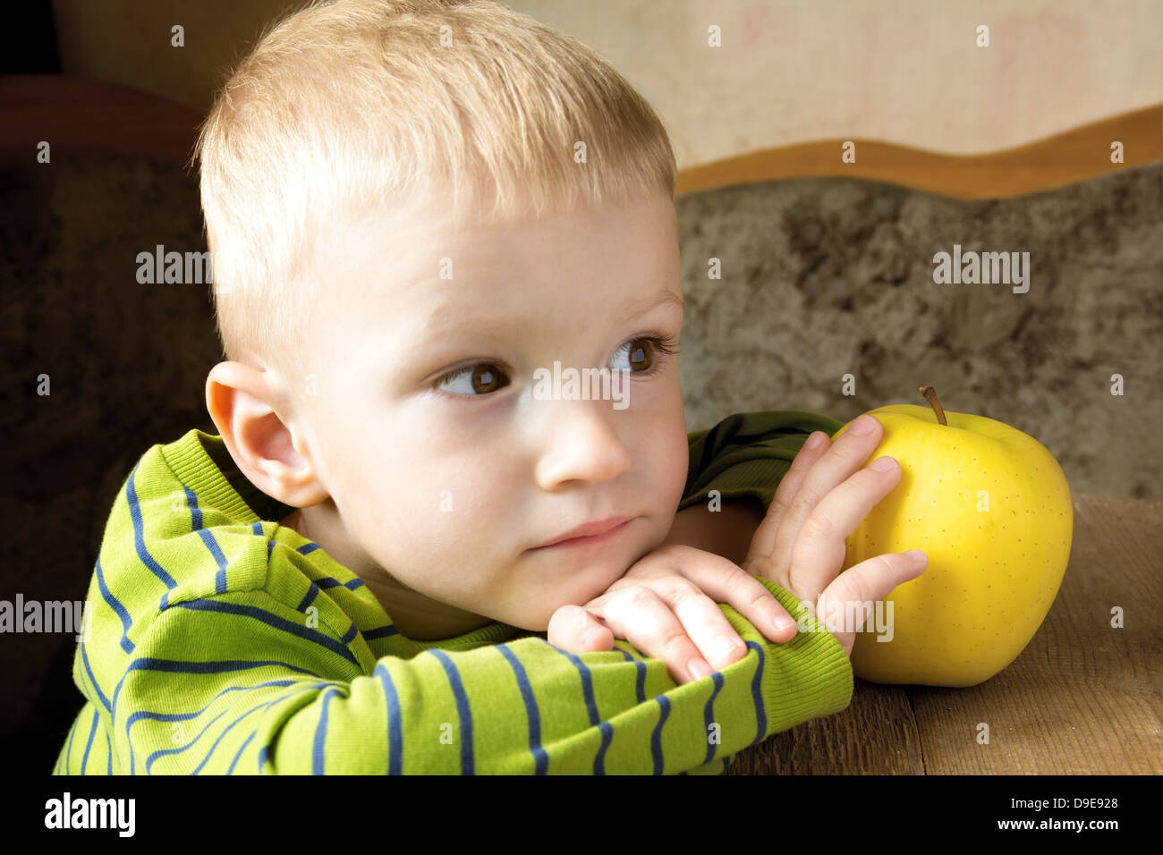 Child dreaming and thinking at home with yellow apple, close up ...